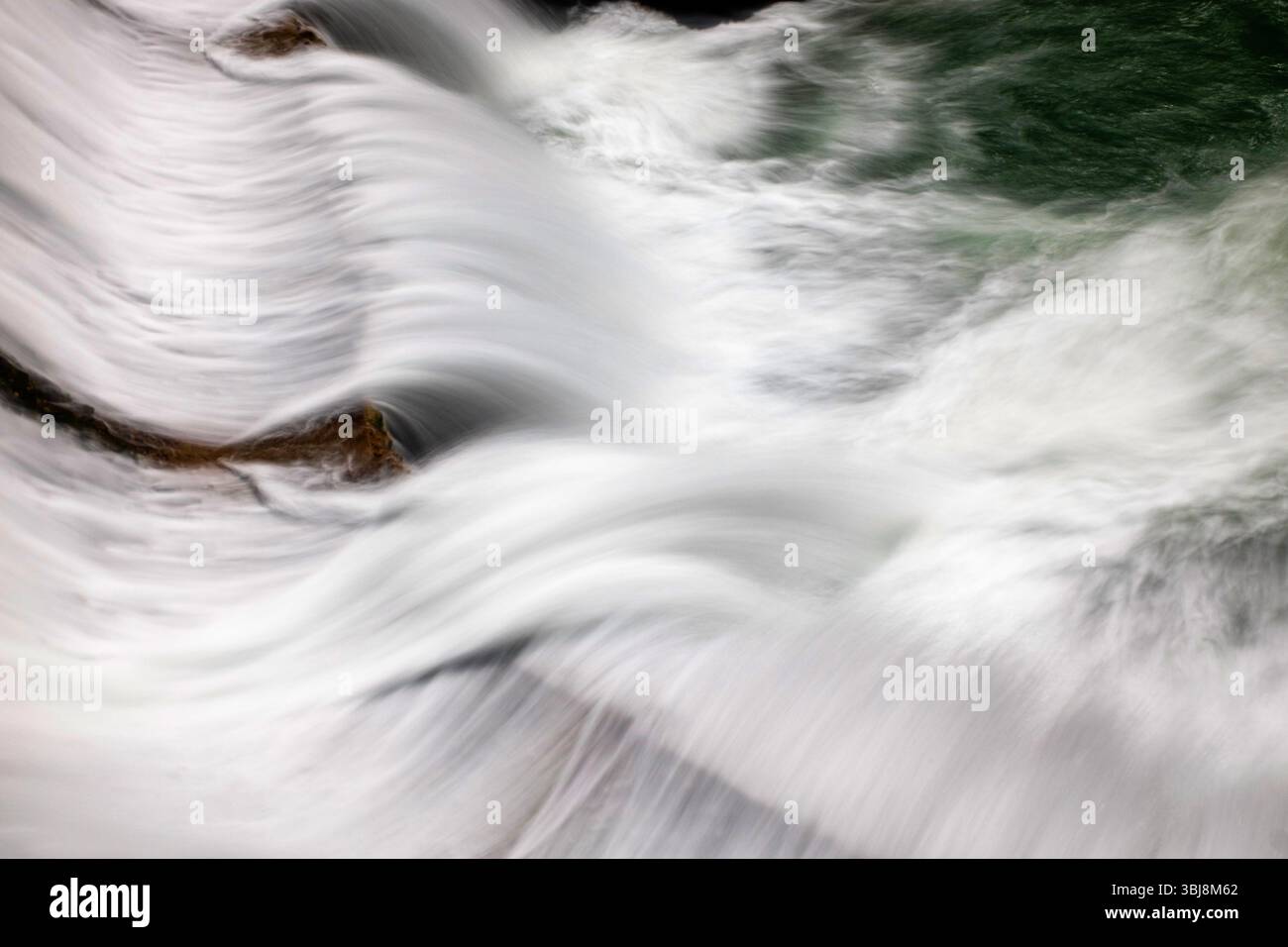 Long exposure of rushing water flowing over rocks in a river, creating ...