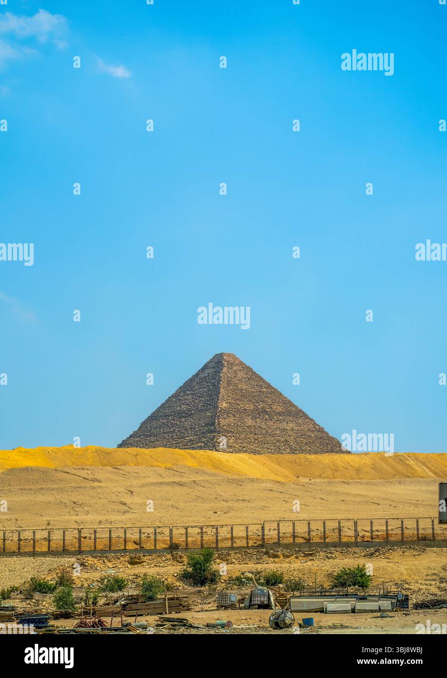 Iconic Egyptian pyramid structure emerging from sandy desert terrain ...