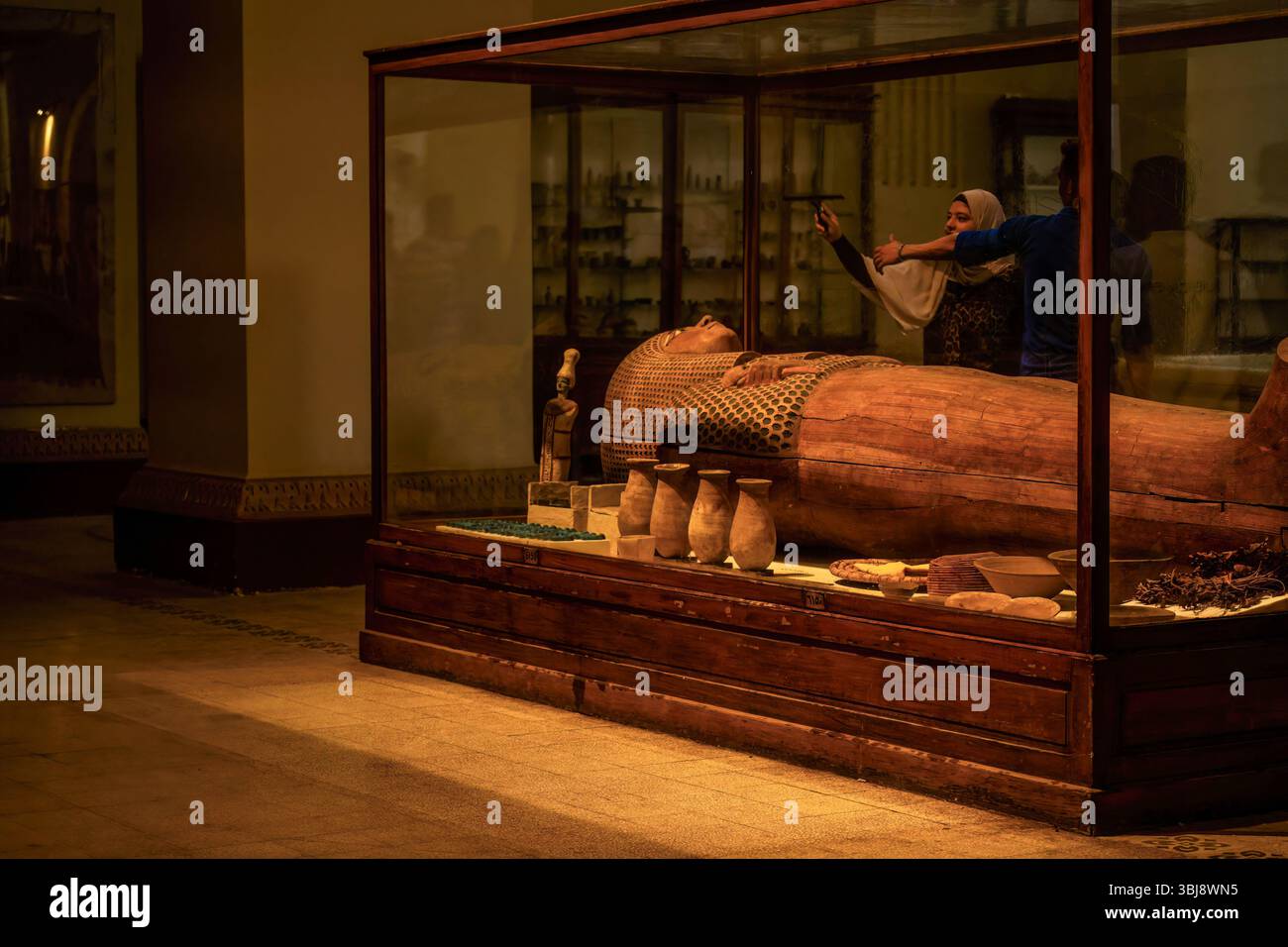 Ancient Egyptian mummy displayed in glass case at museum with canopic ...