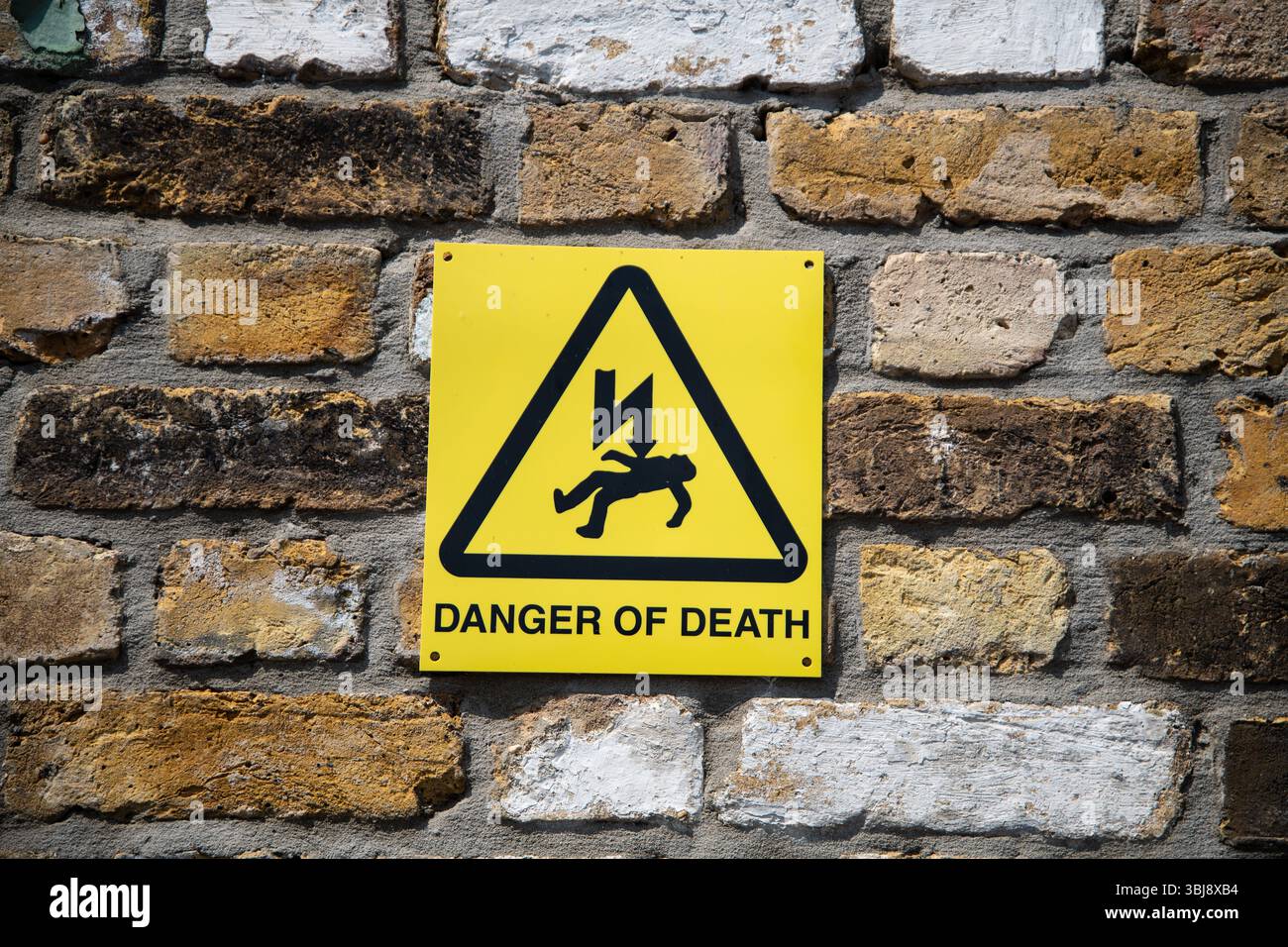 Yellow "Danger of Death" warning sign mounted on a wall, featuring a ...