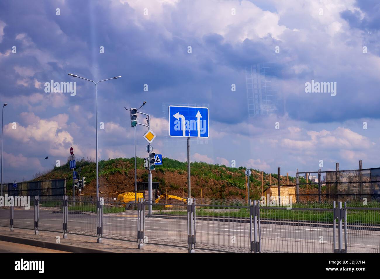 There is a road featuring a blue sign that prominently displays the ...