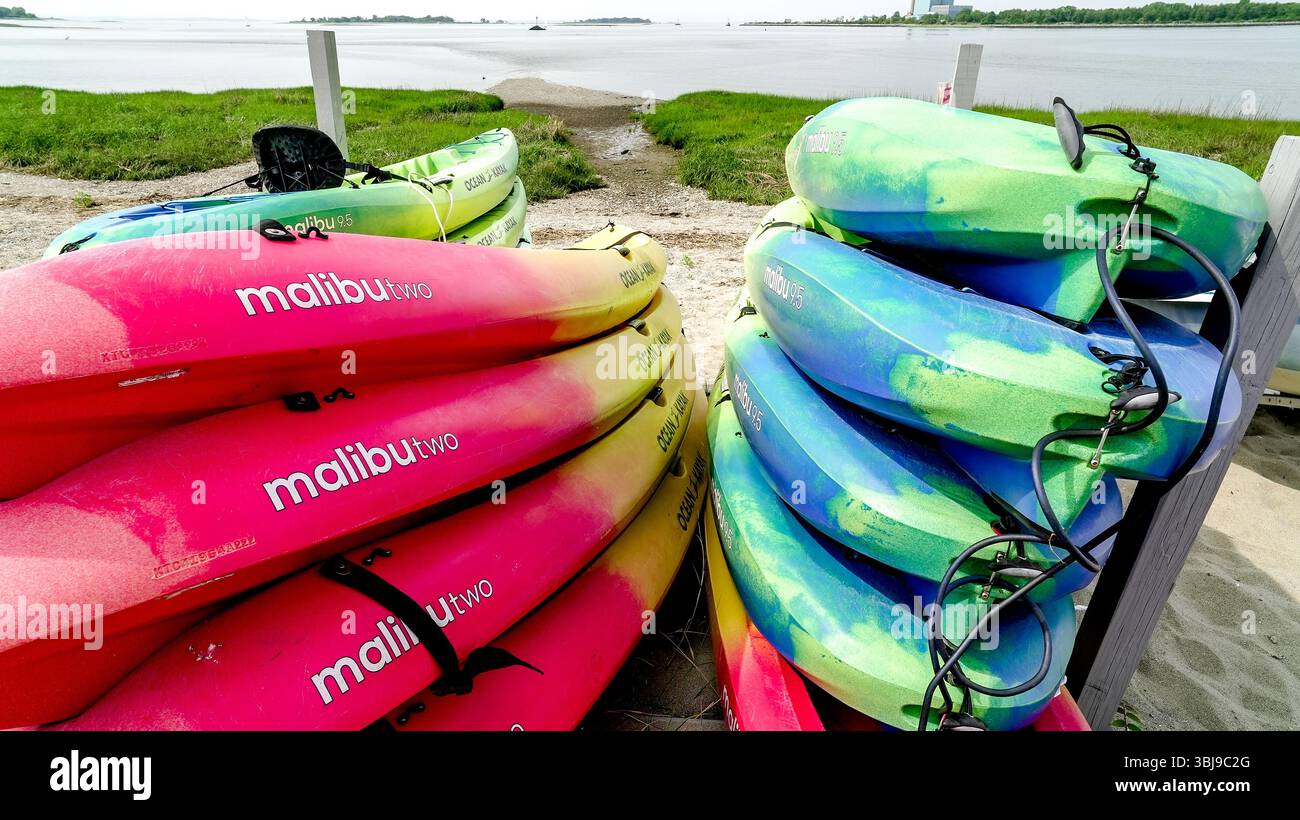 NORWALK, CT, USA - JUNE 13, 2025: Brightly colored kayaks are stacked ...