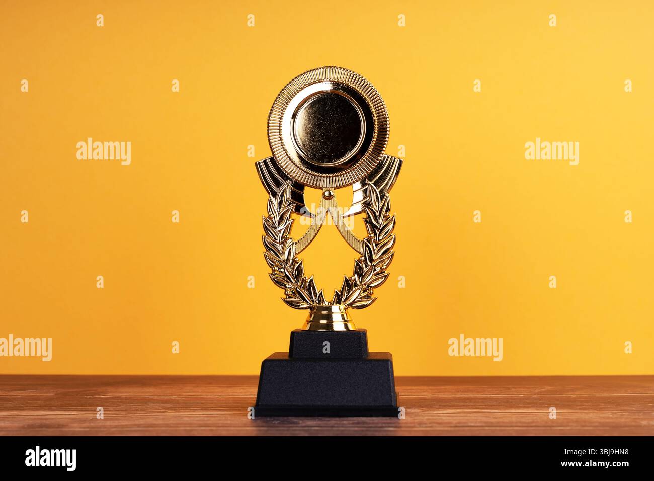 a trophy on a table with a yellow wall background Stock Photo - Alamy