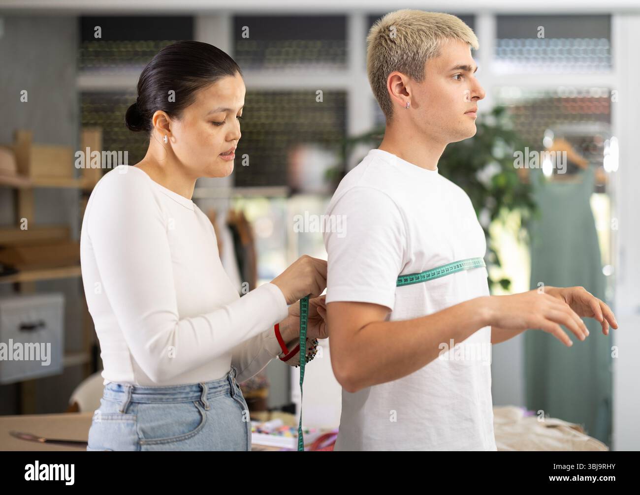 Professional young female fashion designer taking measurements of male ...