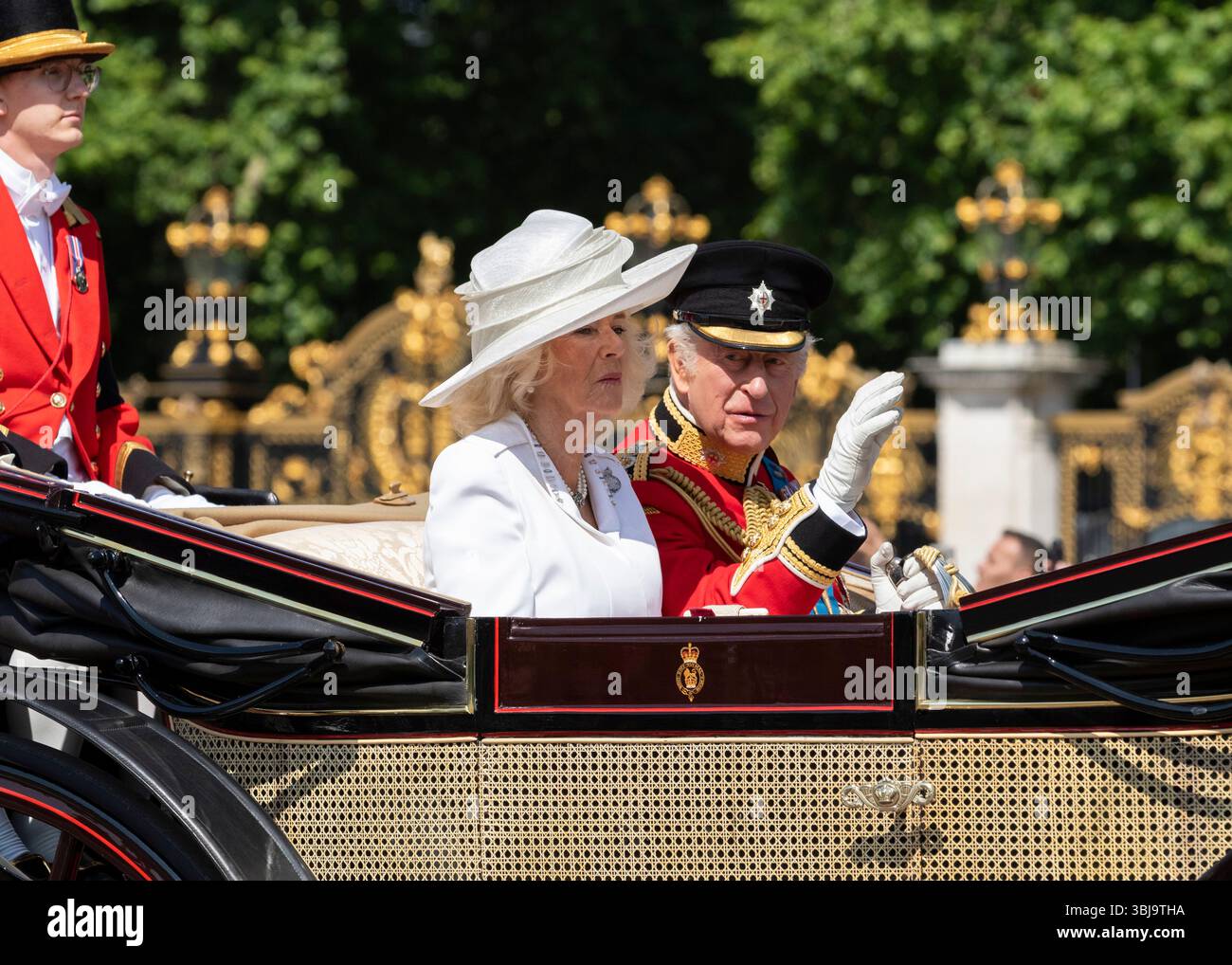 Queen Camilla with a waving King Charles riding in an open top carriage ...