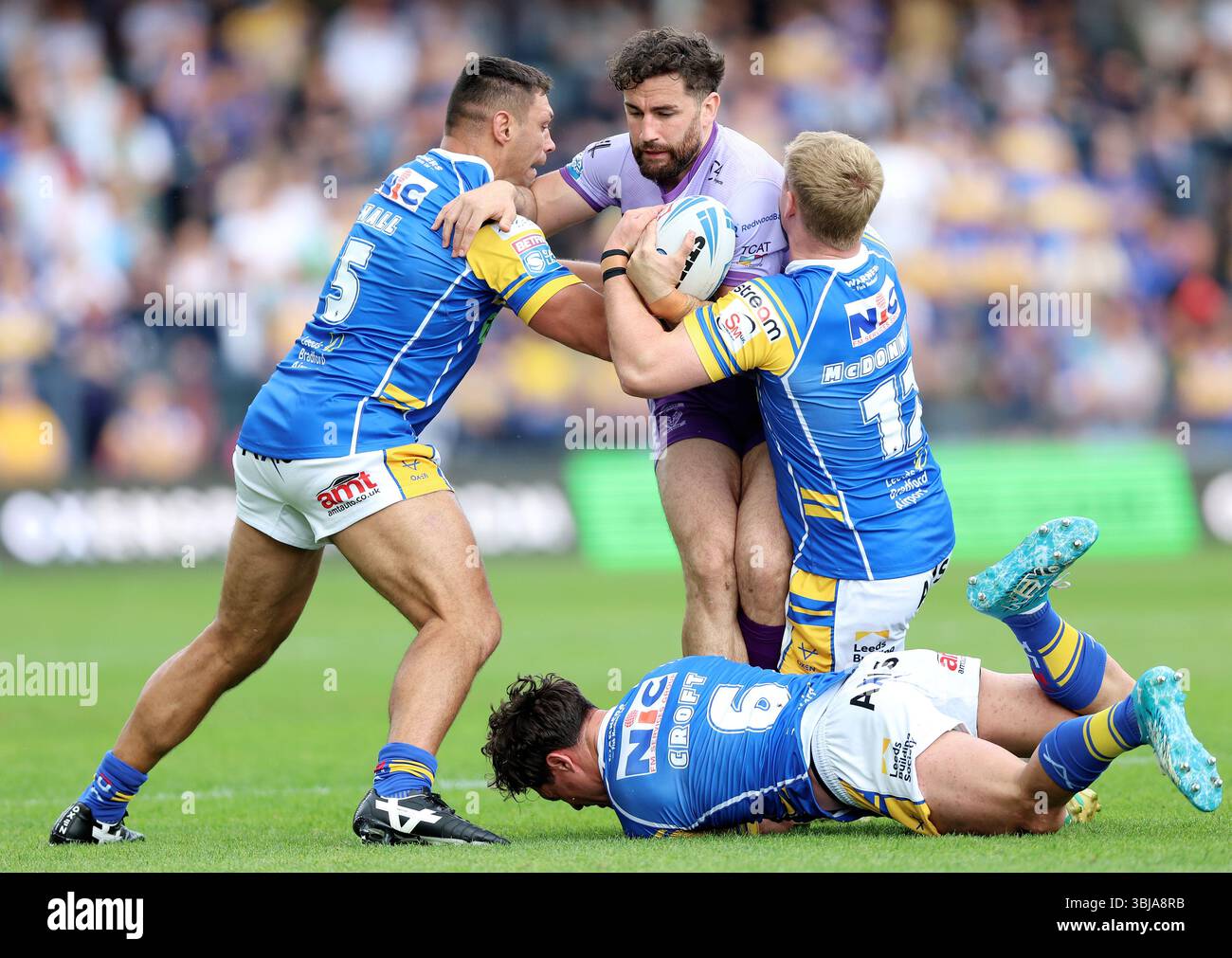 Warrington Wolves' Toby King (centre) is tackled by Leeds Rhinos' Ryan ...