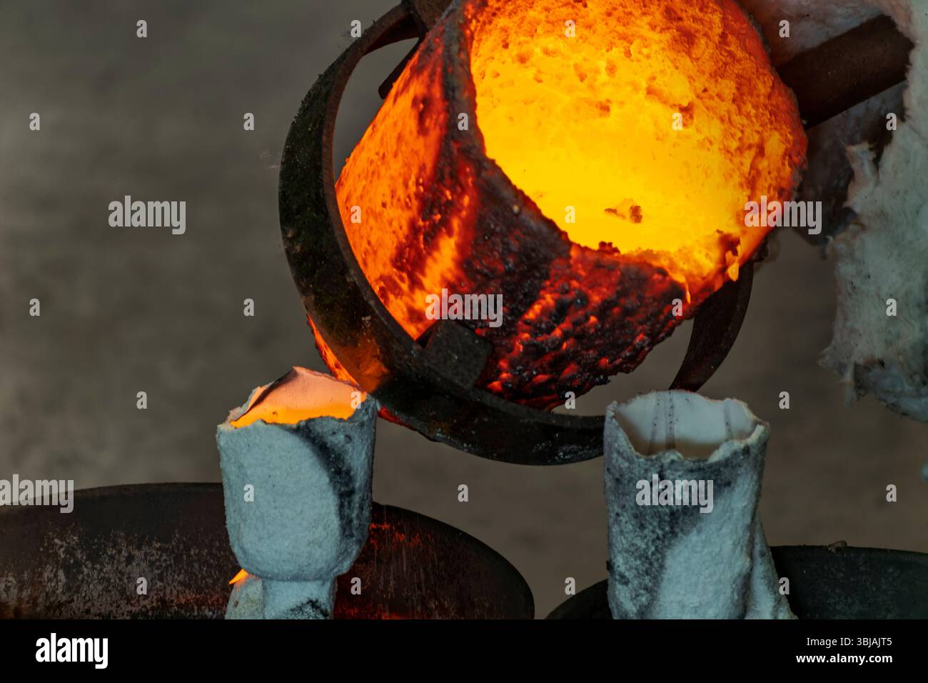 Molten metal from crucible pours into ceramic mold during bronze ...