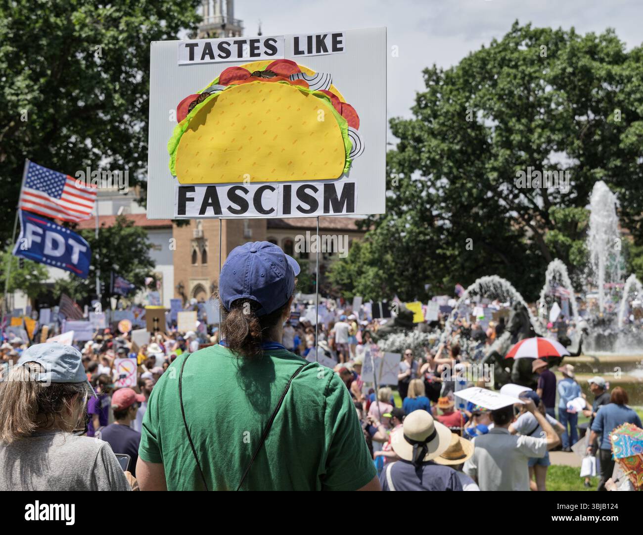 A protest scene with a person holding a sign depicting a taco labeled ...