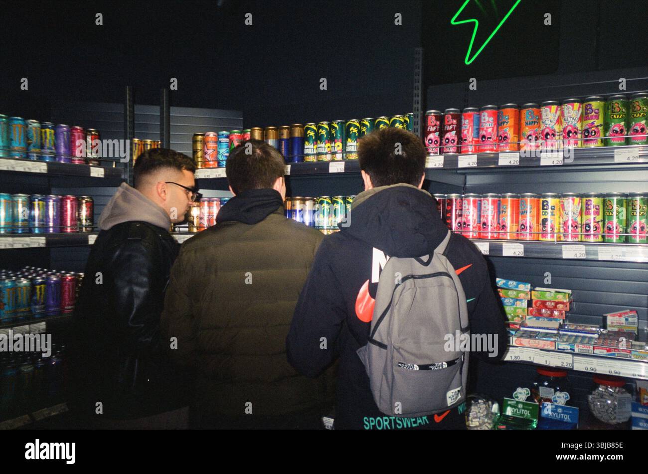 Three young men choosing drinks and snacks in a Japanese candy store ...