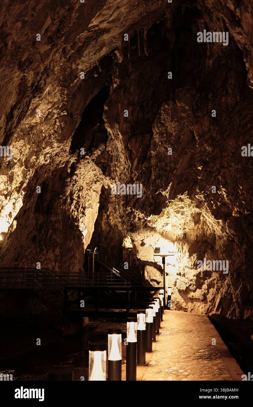 Well-lit path through Stopica Cave with modern lights and rocky ...