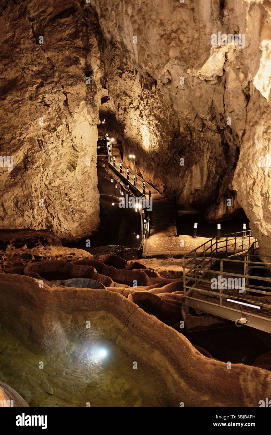 Natural cave pools with greenish water and surrounding lit walkways ...