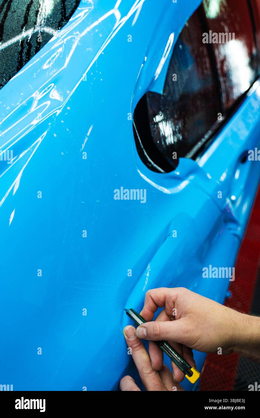Cutting blue PPF with blade. Cutting blue paint protection film with ...