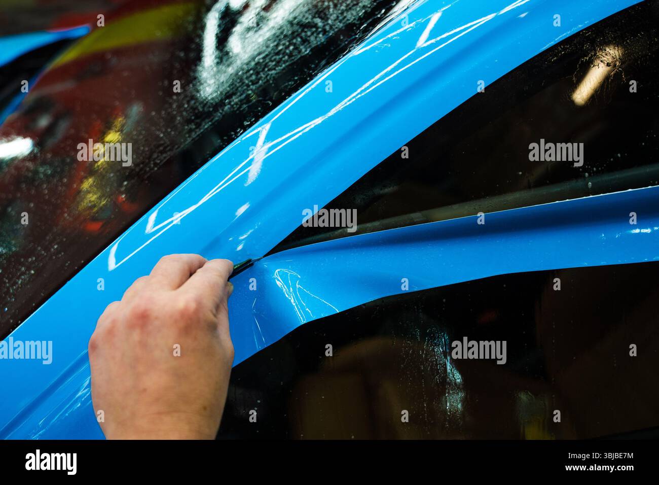 Cutting blue PPF with blade. Cutting blue paint protection film with ...