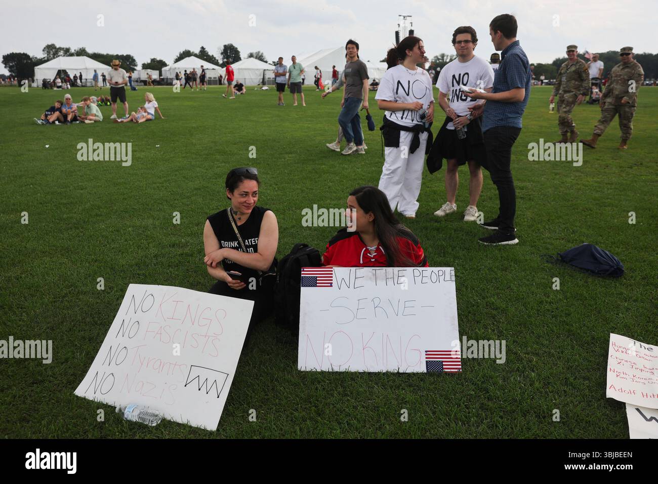 Spectators sit with signs on the National Mall ahead of a military ...