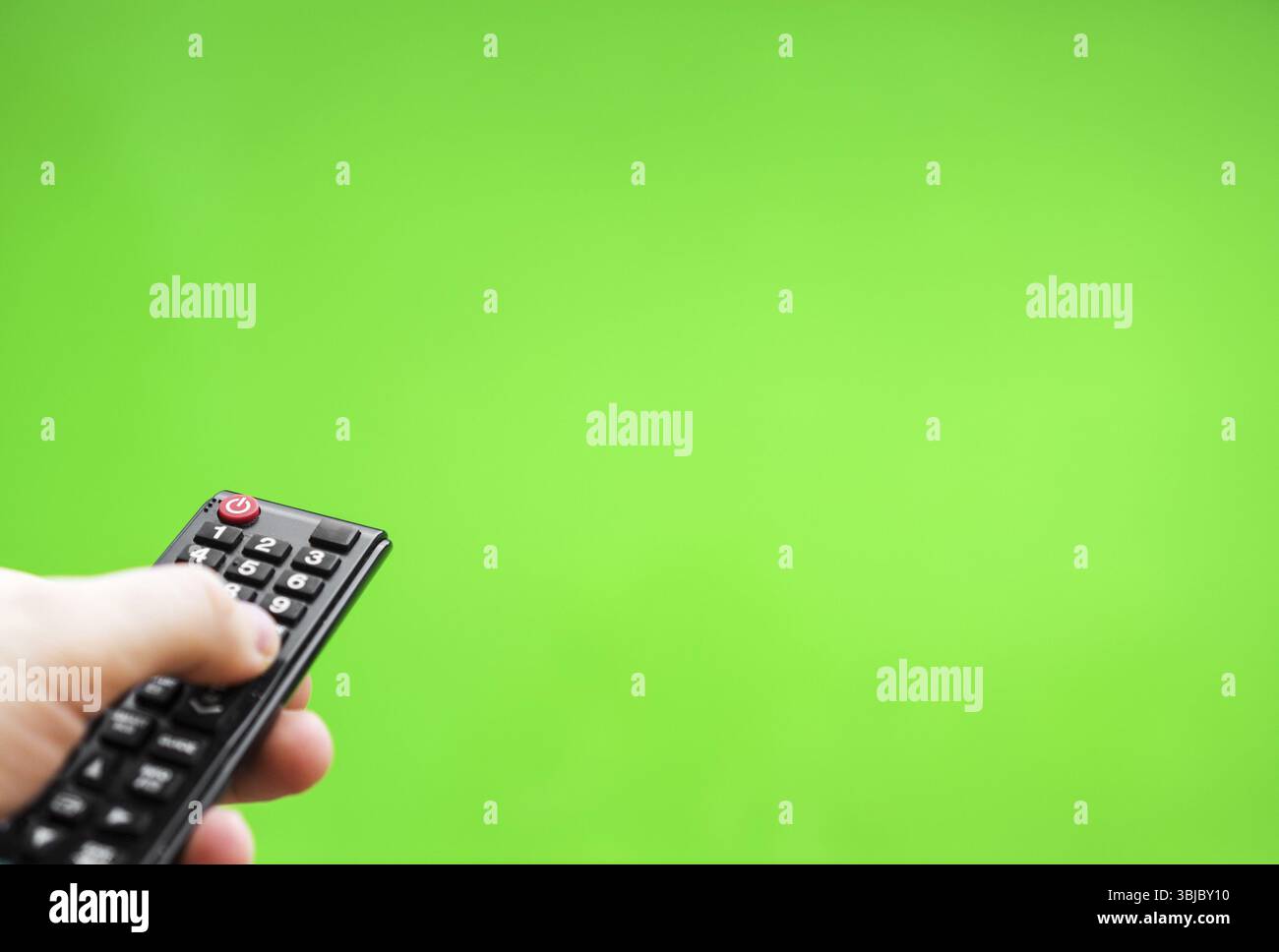 Male hand with TV remote control over green screen. Place for your ...