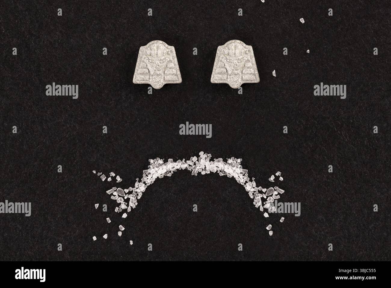Drug abuse and addiction. MDMA crystal and ecstasy pill forming a sad ...