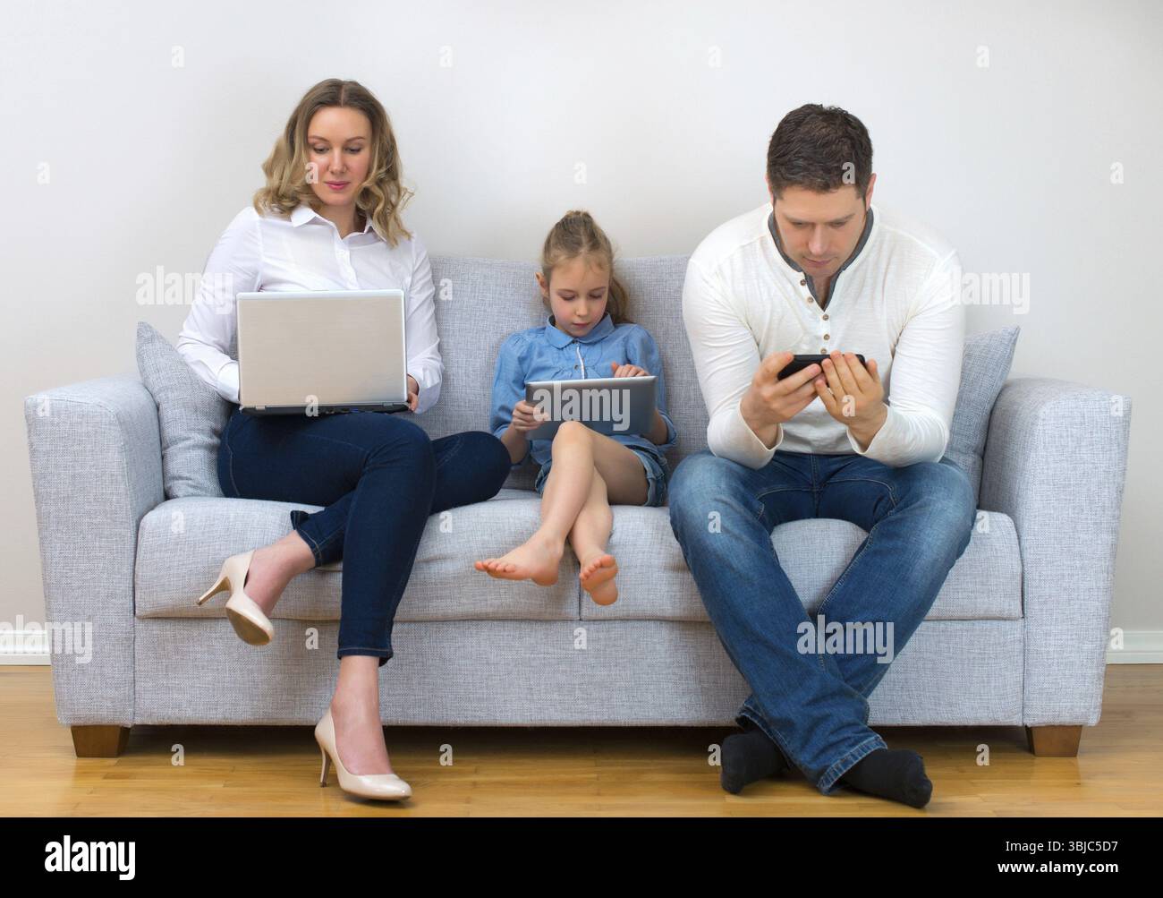 Modern family values. Father, mother and daughter using electronic ...