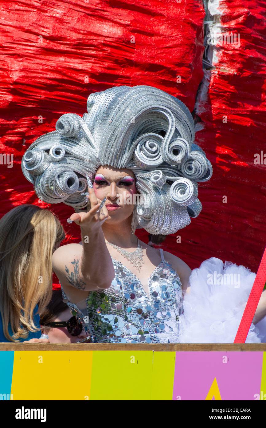 A drag queen leads a mirrored float adorned with sequins and a silver ...