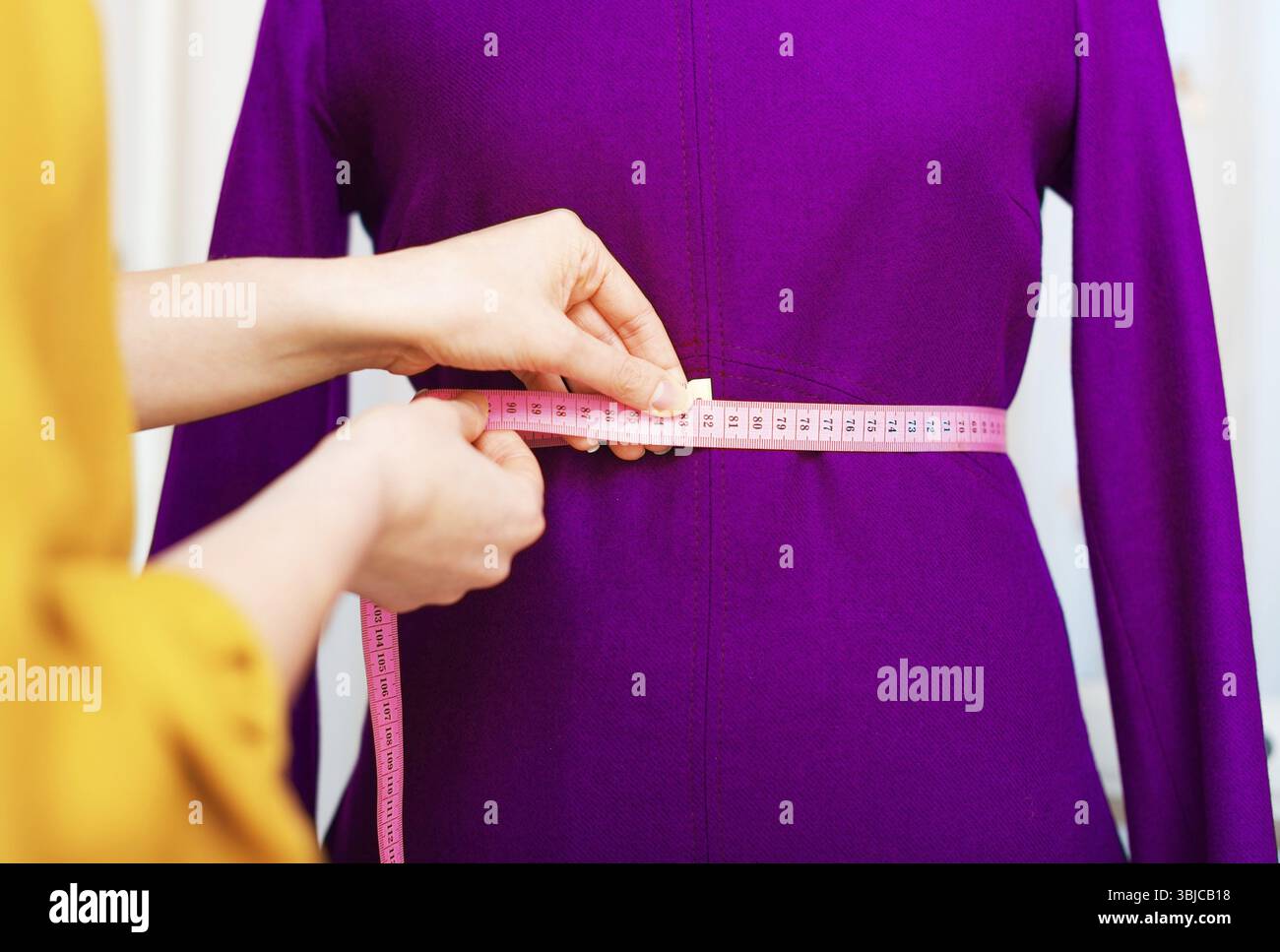 Fashion designer with measuring tape working on mannequin Stock Photo ...