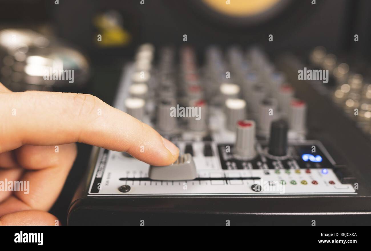 Sound engineer using main control fader of studio mixer Stock Photo - Alamy