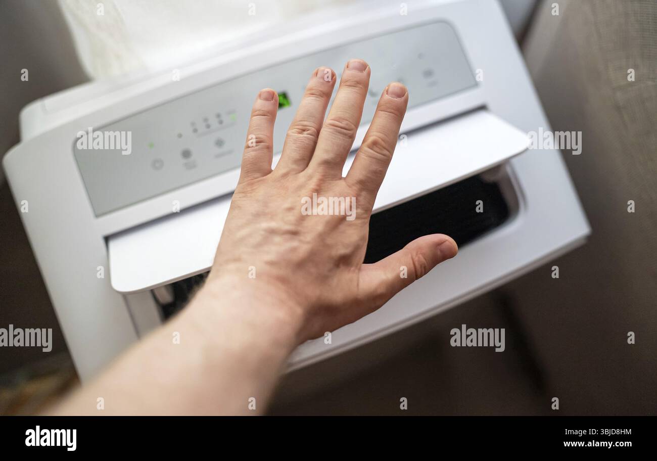 Male hand checking air flow of floor standing mobile air conditioner ...