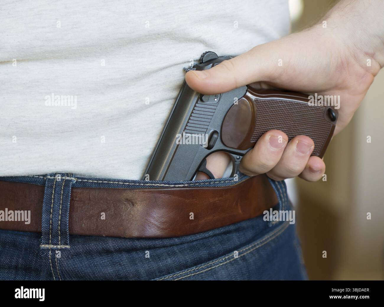 Man hiding gun behind his back Stock Photo - Alamy