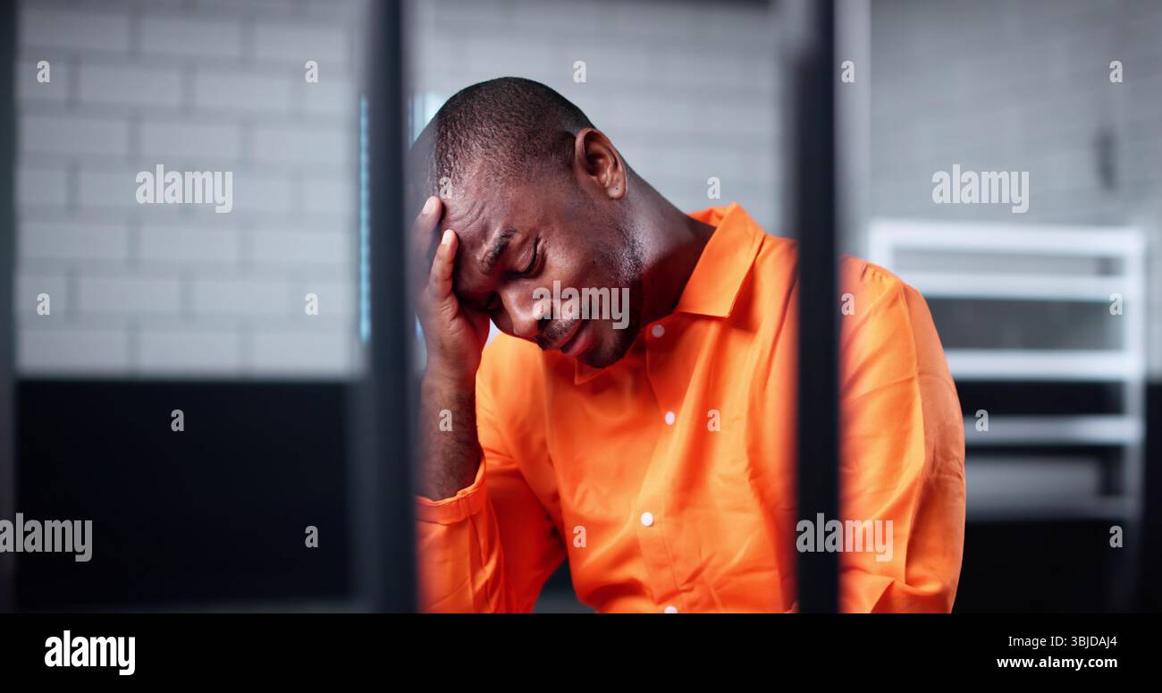 African American Inmate In Orange Uniform Crying Behind Prison Bars ...
