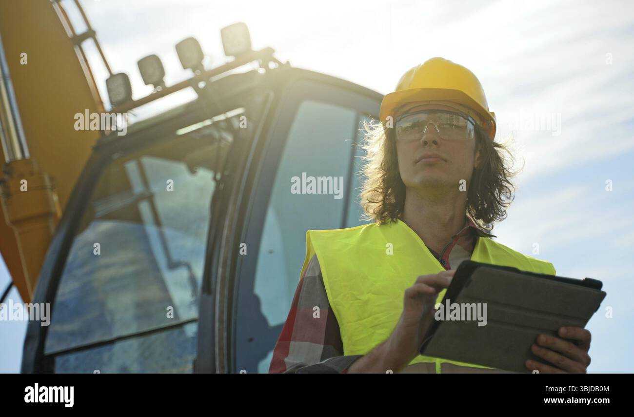 Excavator operator in hard hat using tablet pc Stock Photo - Alamy