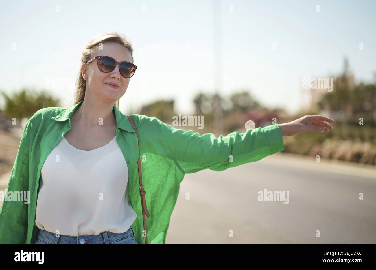 Pretty woman hitch-hiking on the roadside Stock Photo - Alamy