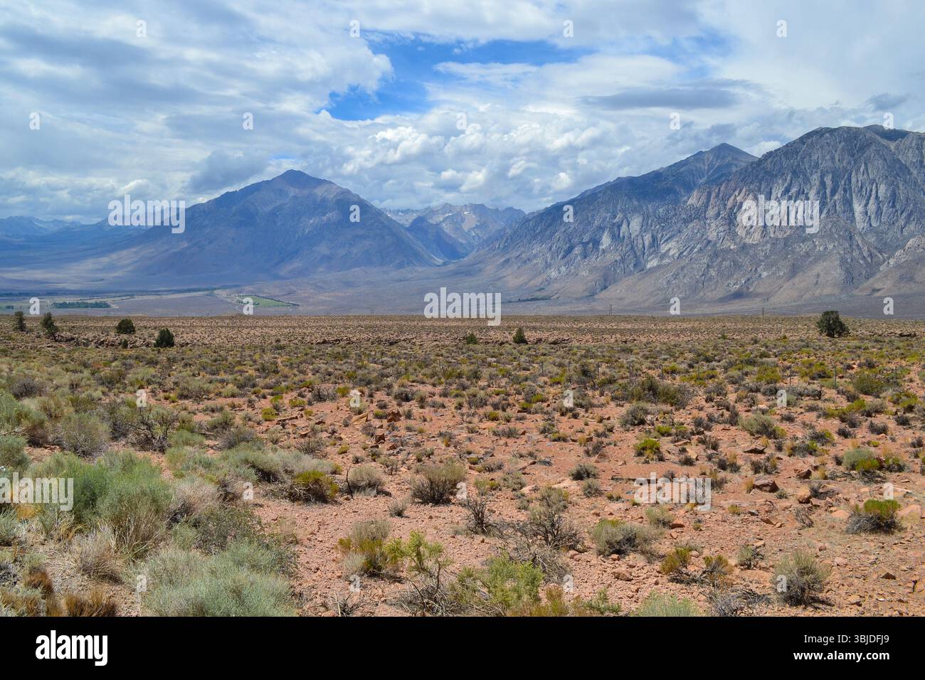 Expansive desert terrain stretches under a vast sky filled with clouds ...