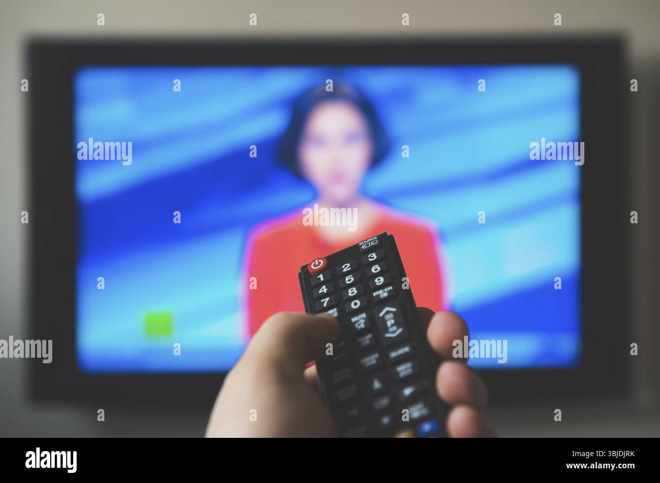 Male hand holding TV remote control. News block Stock Photo - Alamy