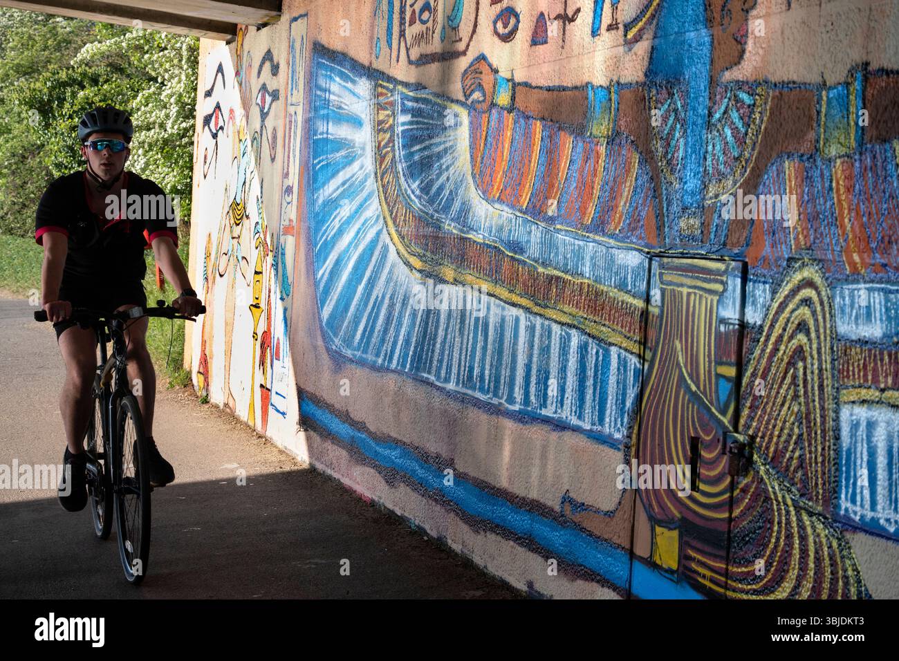 Graffiti and cyclist beneath Donnington bridge over the Thames. This is ...