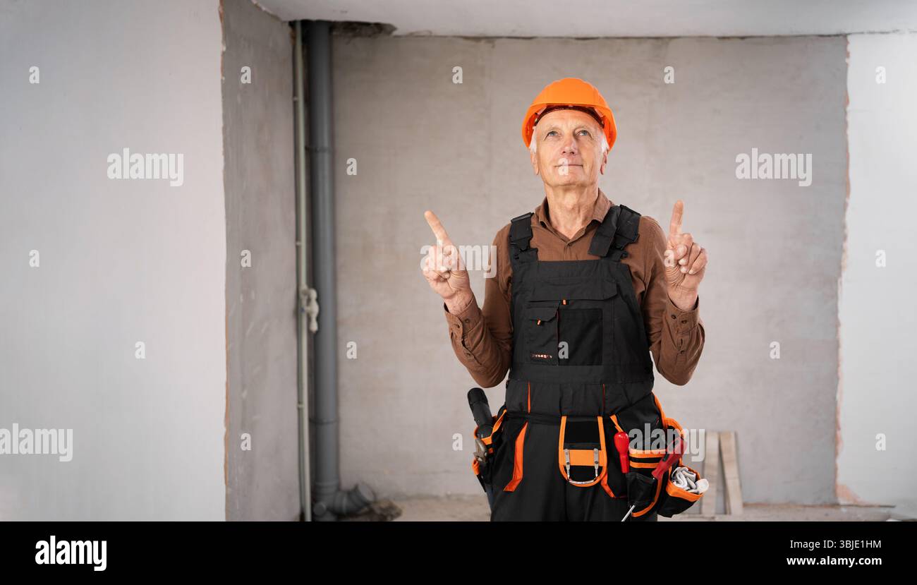 Elderly builder or construction worker pointing up with fingers over ...