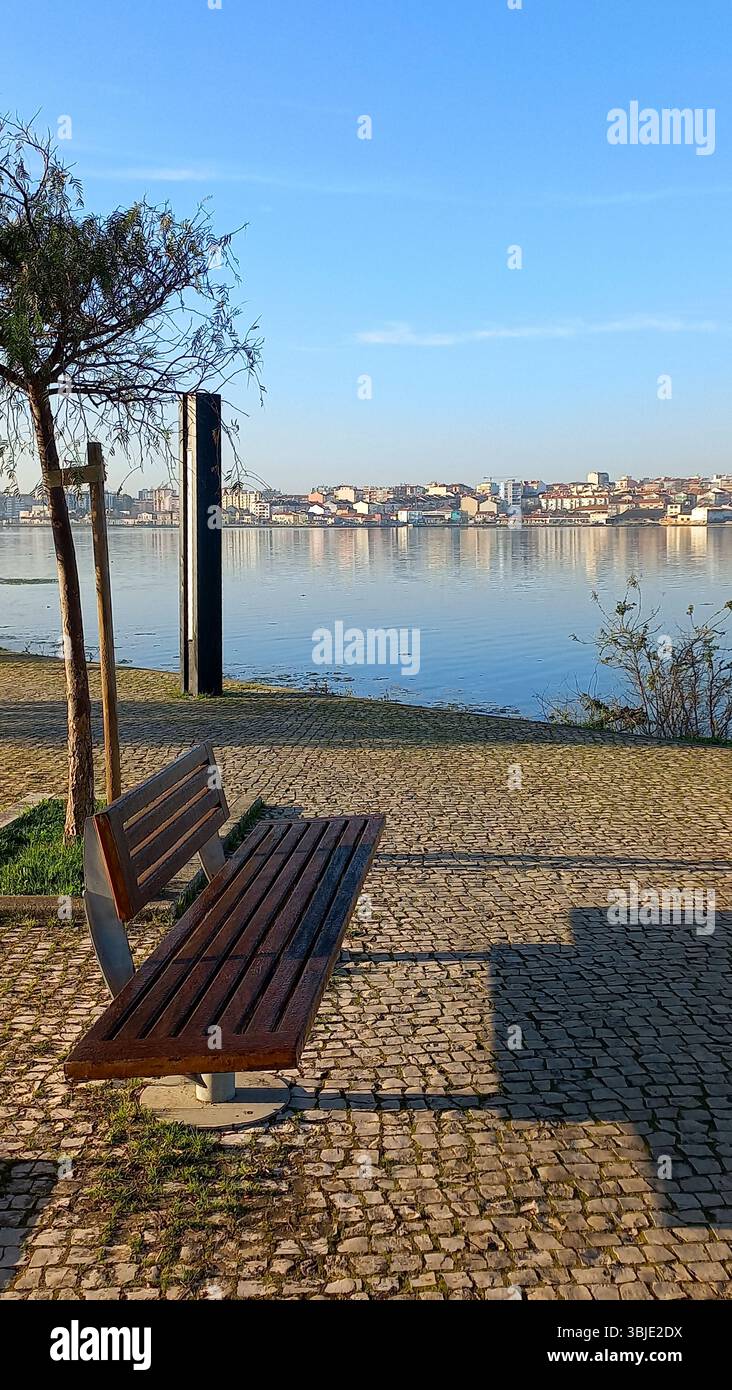 Quiet dawn scene at Seixal promenade featuring empty bench cobbled path ...