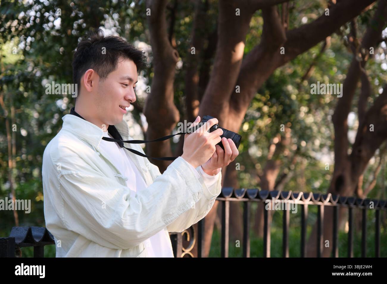 Chinese young man take photos use camera outdoor, side view Stock Photo ...