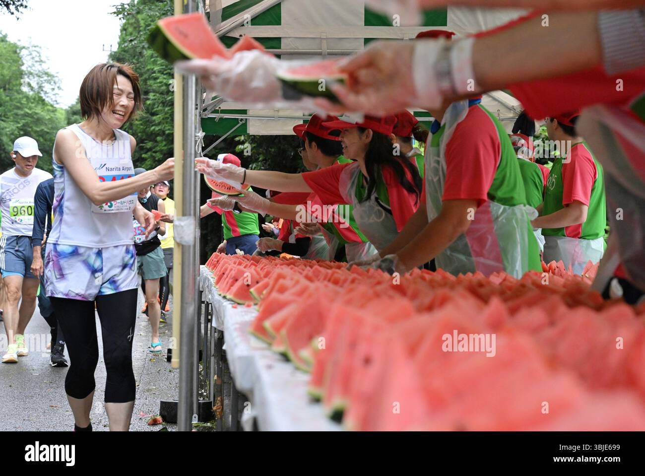 Runners receive watermelons at the water station. The Tomisato ...
