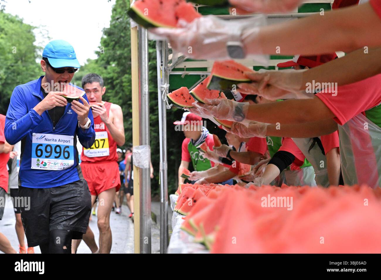 Runners receive watermelons at the water station. The Tomisato ...