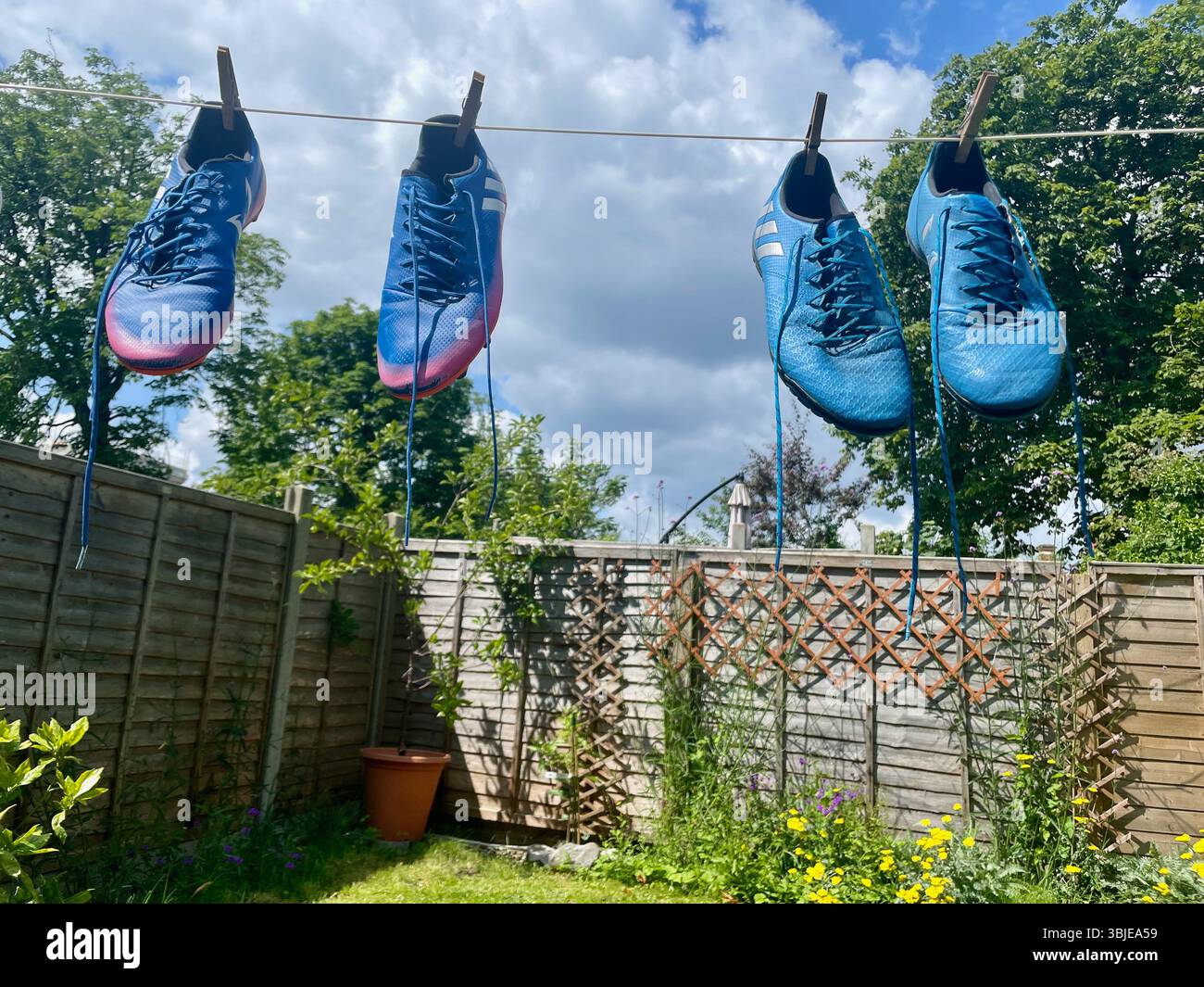 blue coloured adidas messi football boots hanging form a washing line ...