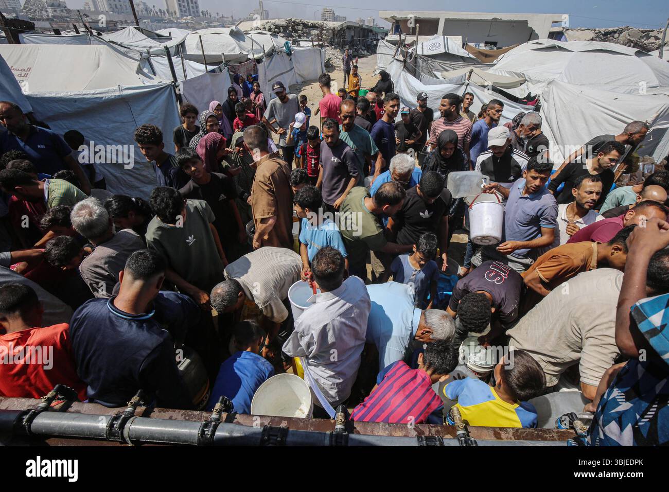 Palestinians carry jerry cans filled with water distributed by a water ...