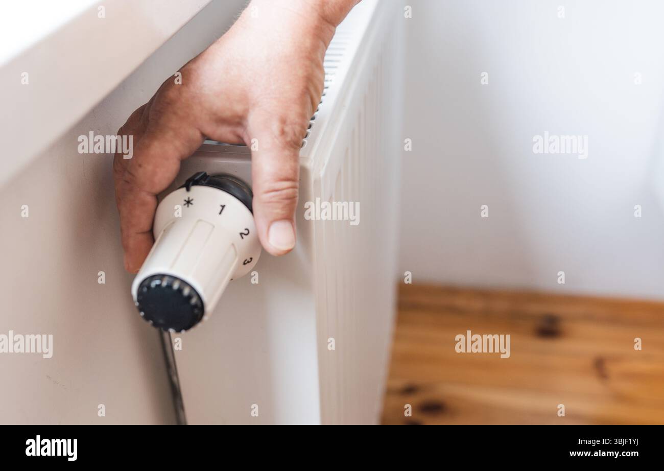 Hand regulates the heat in the house on the radiator handle Stock Photo ...