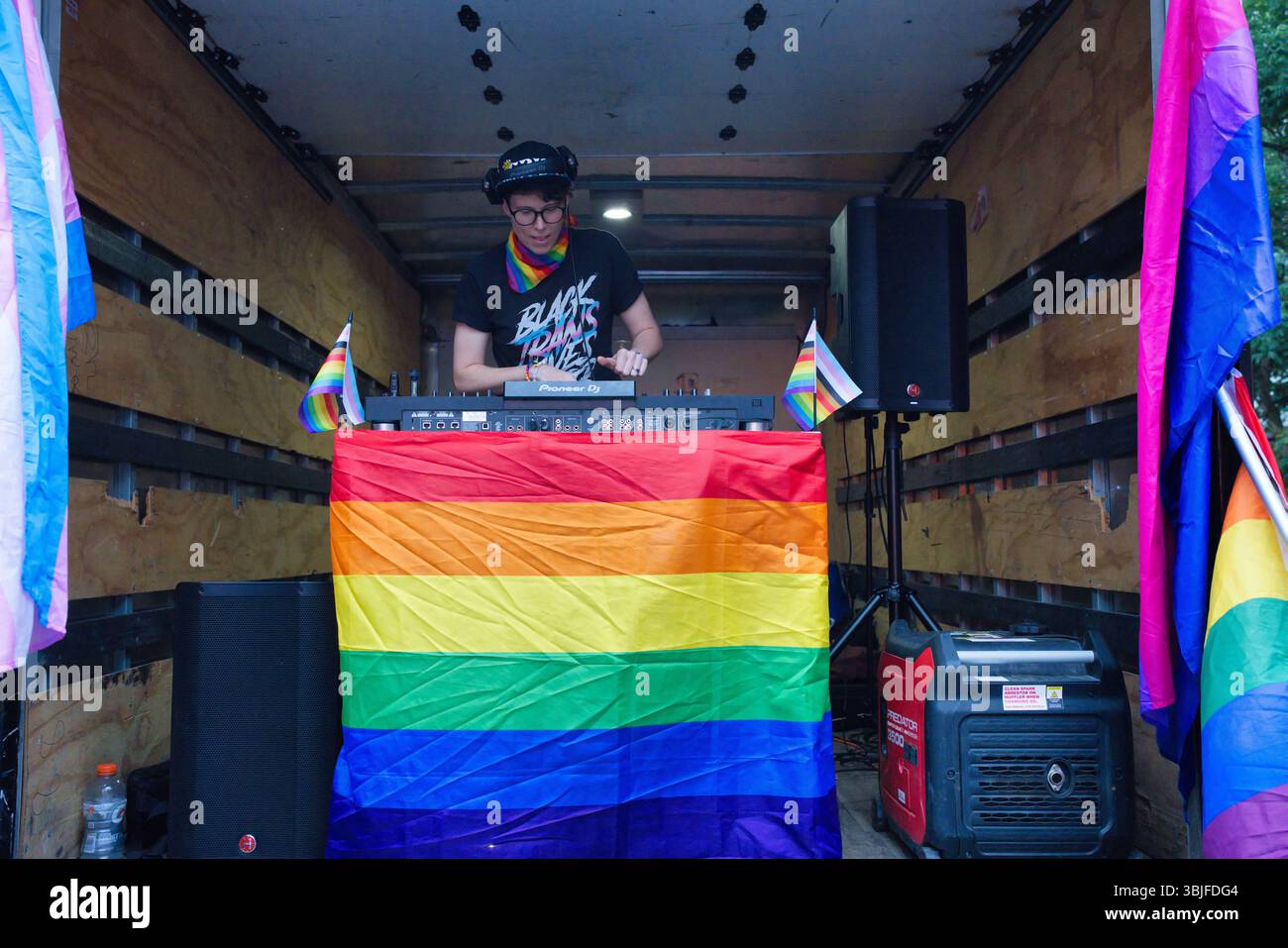 A person wearing a black t-shirt and headphones DJs at a mixer inside a ...