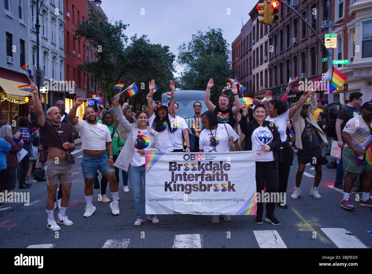 A diverse group of people march in a Pride parade, holding rainbow ...