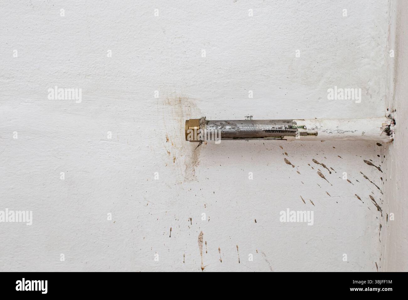 Cut out metal pipe with dirty water splashes on white stucco wall ...