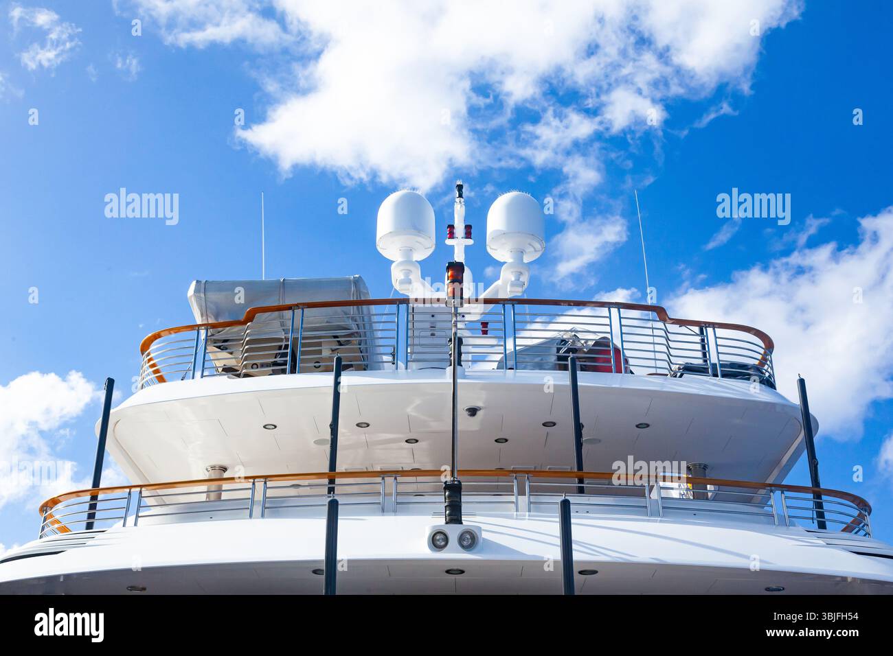 The stern of a luxury yacht with stainless steel railings and a mast at ...