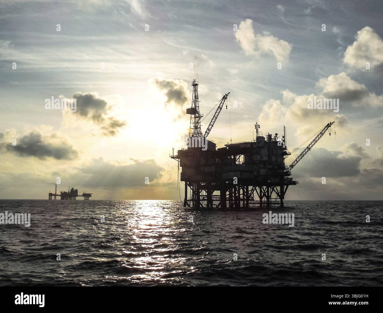 Offshore oil platform at sunset Stock Photo - Alamy