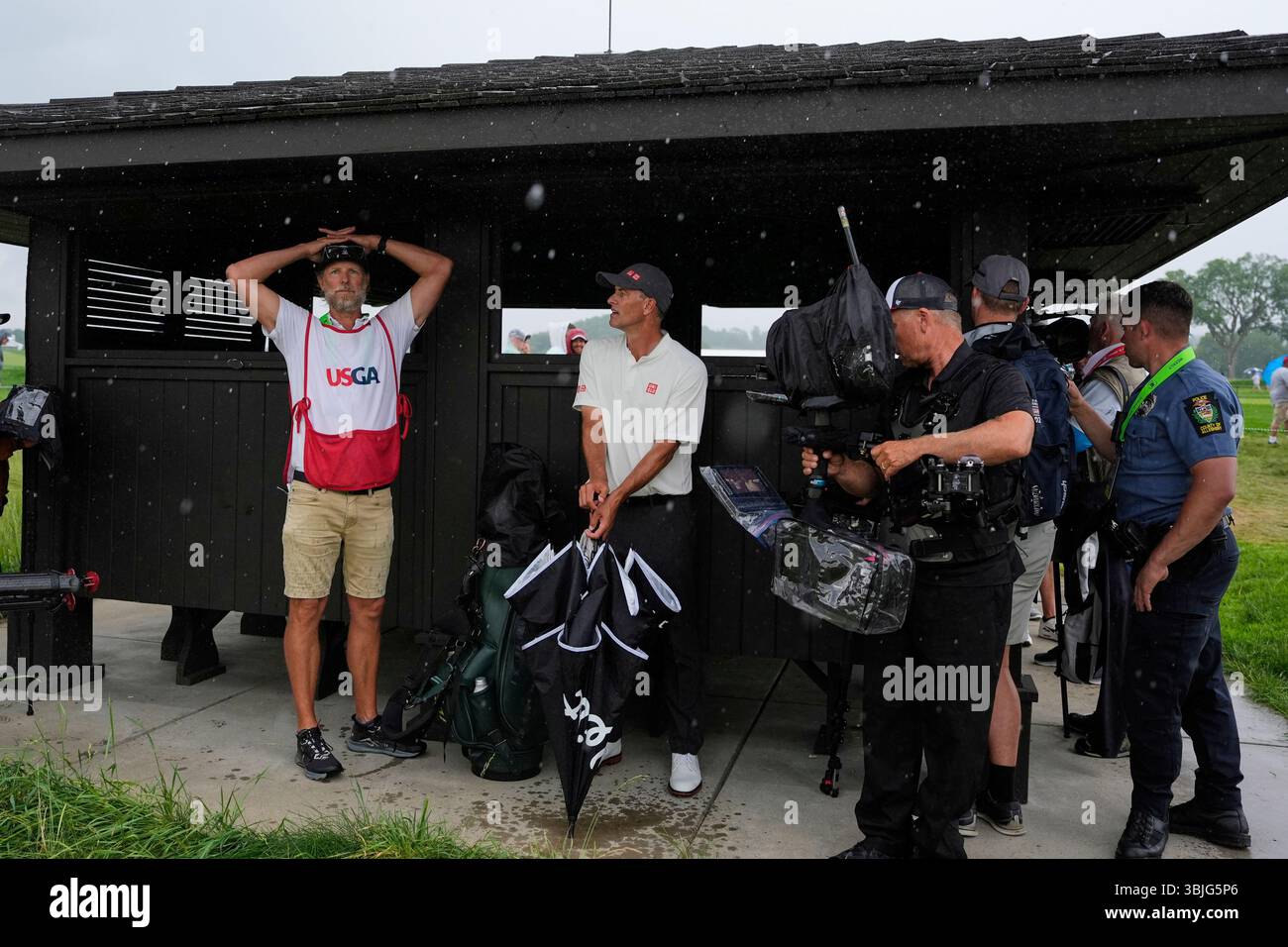 Adam Scott, of Australia, takes shelter from the rain during a weather ...