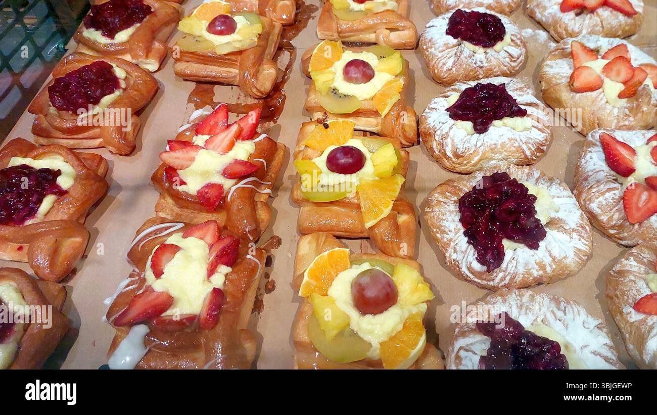 Colorful sweet pastries are neatly arranged in rows at a bakery. Each ...
