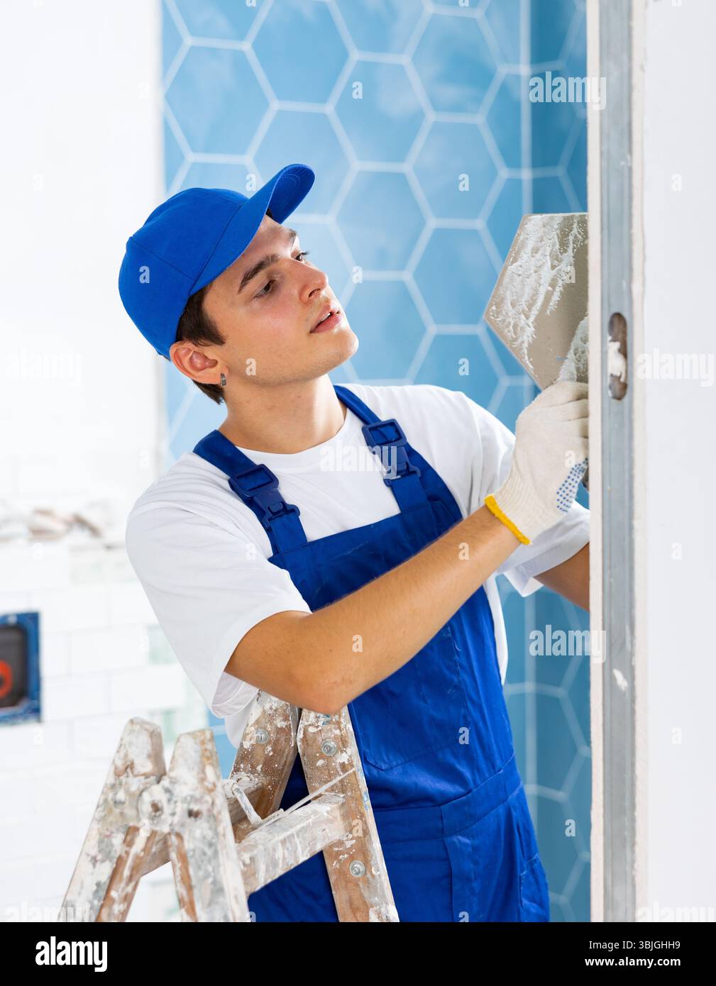 Young tiler working with ceramic tiles for interior decoration of ...