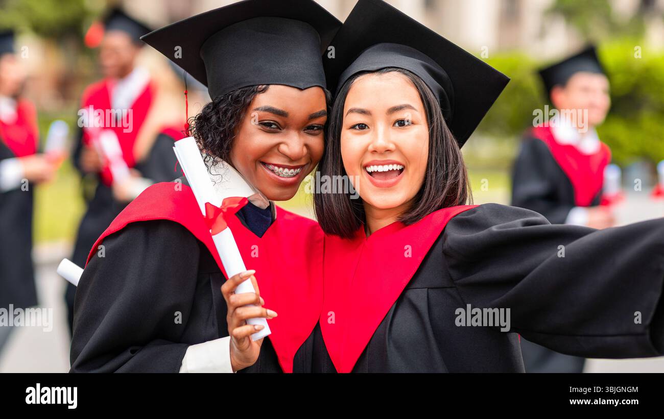 Cheerful young ladies in graduation robes taking selfie Stock Photo - Alamy