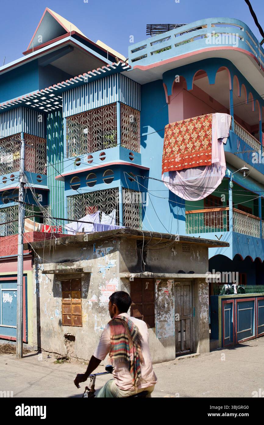 A man cycles past a colourful residential building in Rajshahi ...